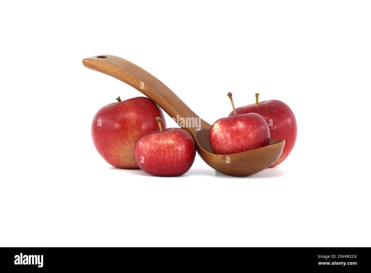 Red apples, one placed in a carved wooden spoon isolated on a white ...