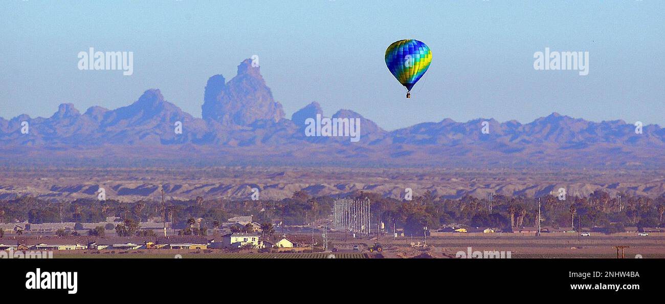 A hot air balloon glides over Arizona's Yuma Valley with Picacho Peak ...