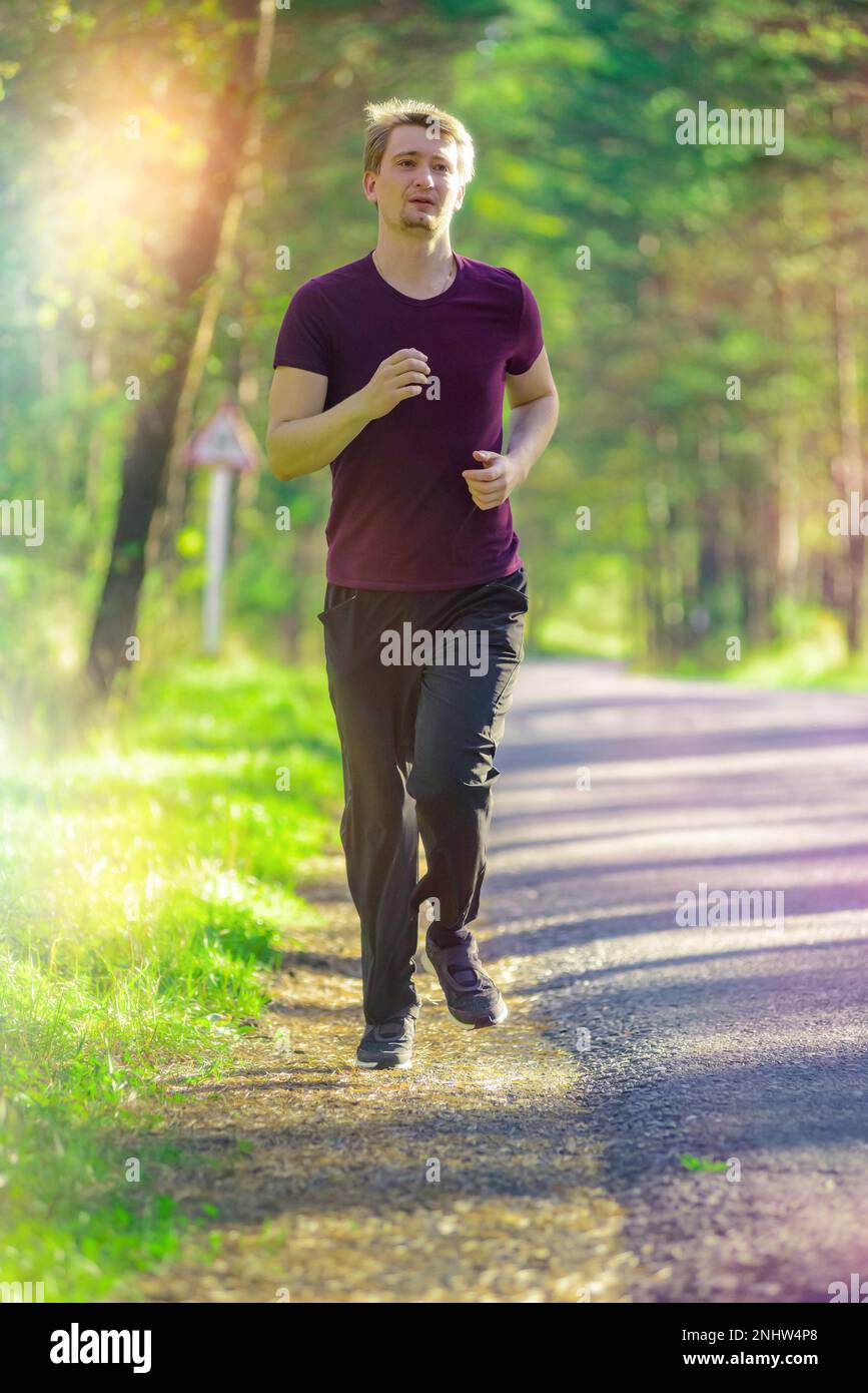 Running man jogging in city park at beautiful summer day. Sport fitness ...