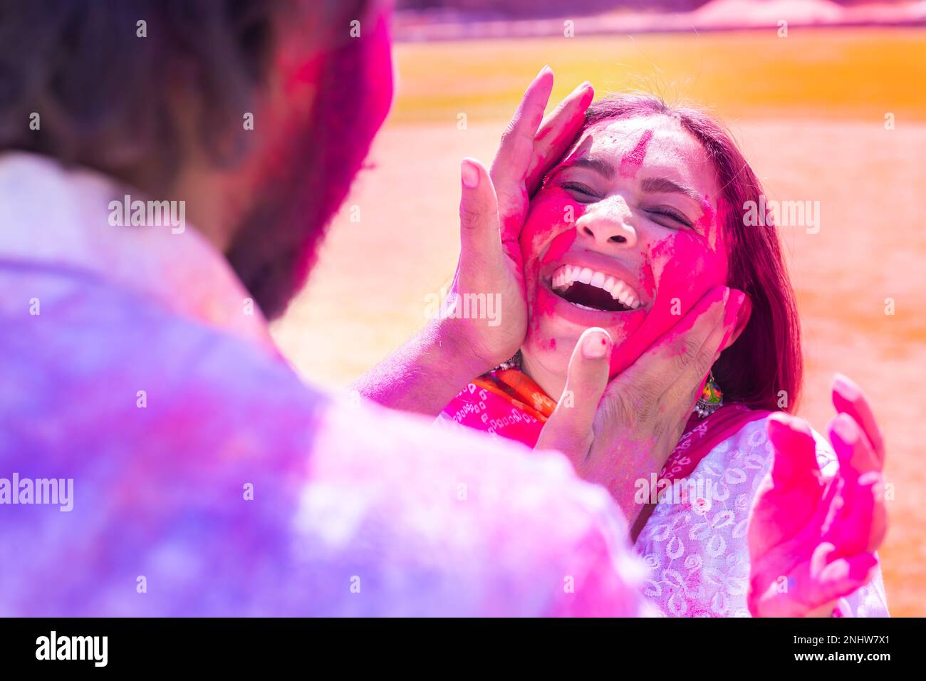 Happy young Indian couple having fun playing with colorful powder color ...
