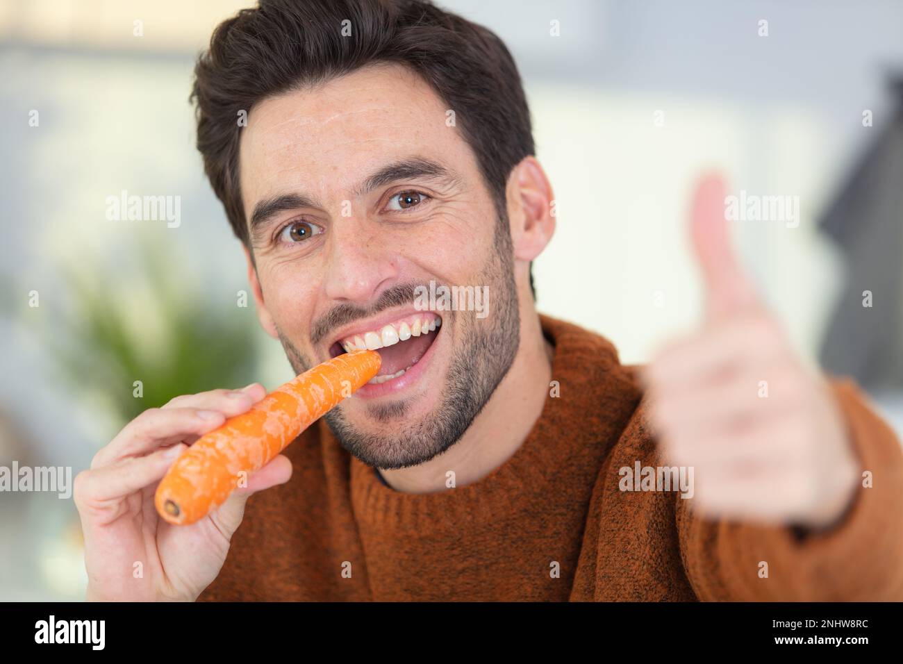 man eating carrot and holding his thumb up Stock Photo - Alamy