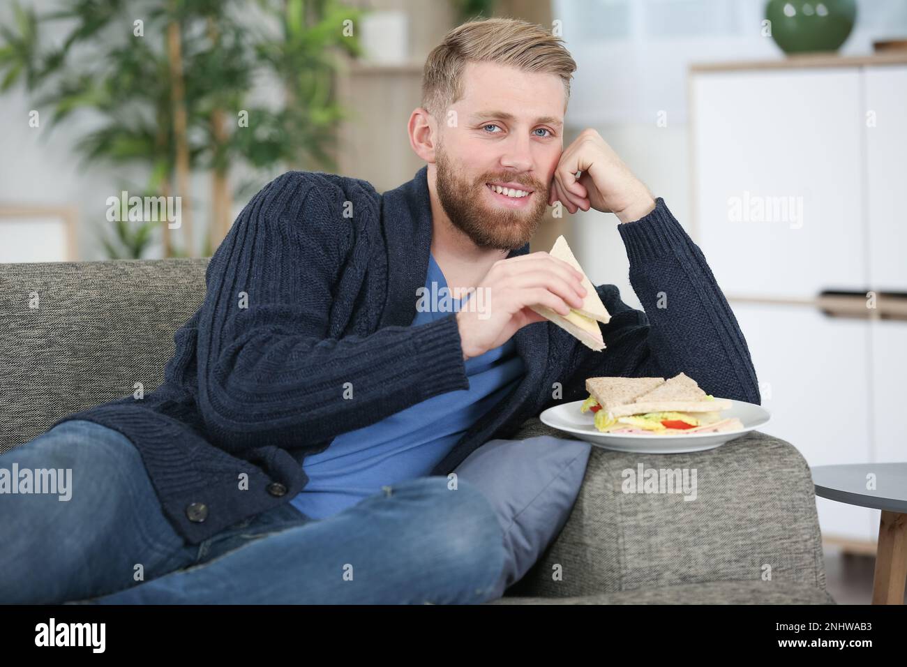 man eating a sandwich at home on the couch Stock Photo - Alamy