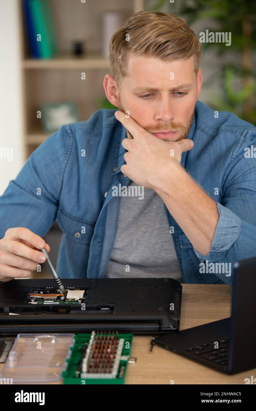 thoughful man is repairing laptop motherboard Stock Photo - Alamy