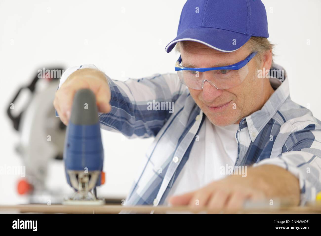 mature man carpenter builder working with electric jigsaw and wood ...