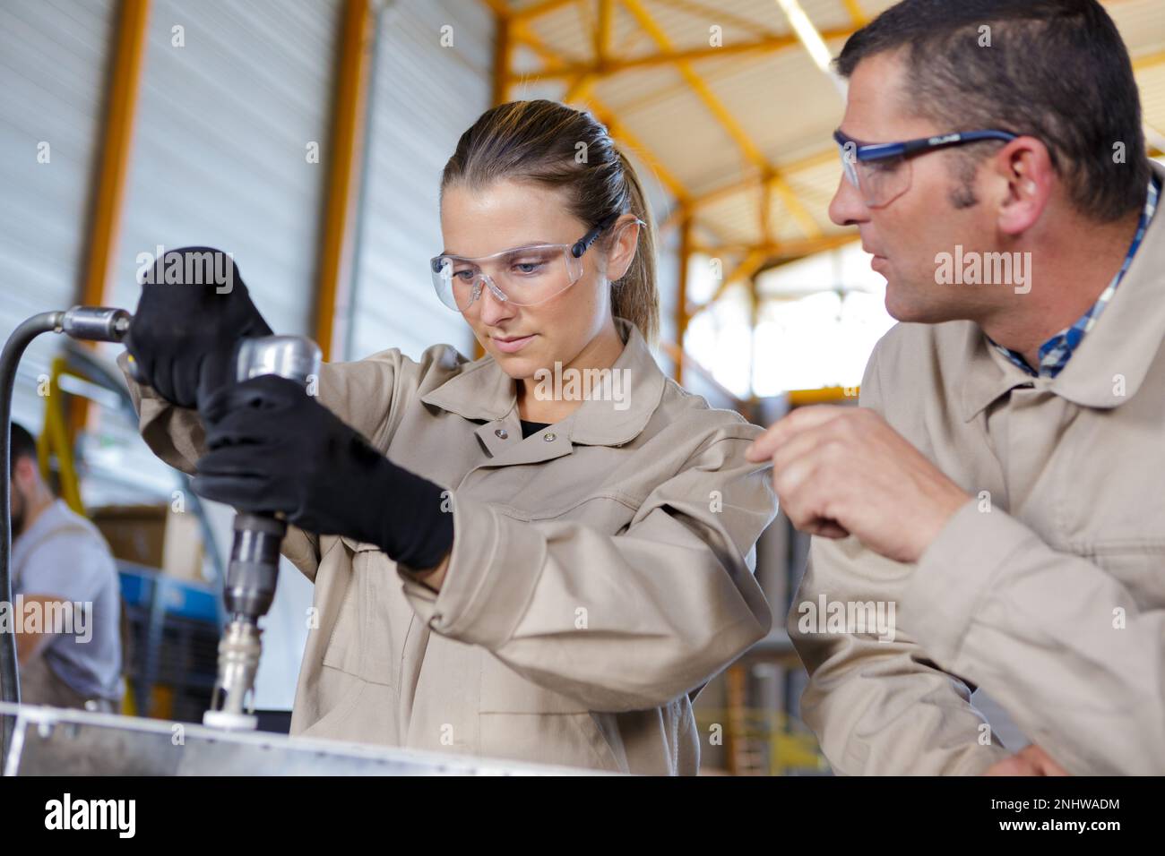 female apprentice using drill under supervision Stock Photo - Alamy