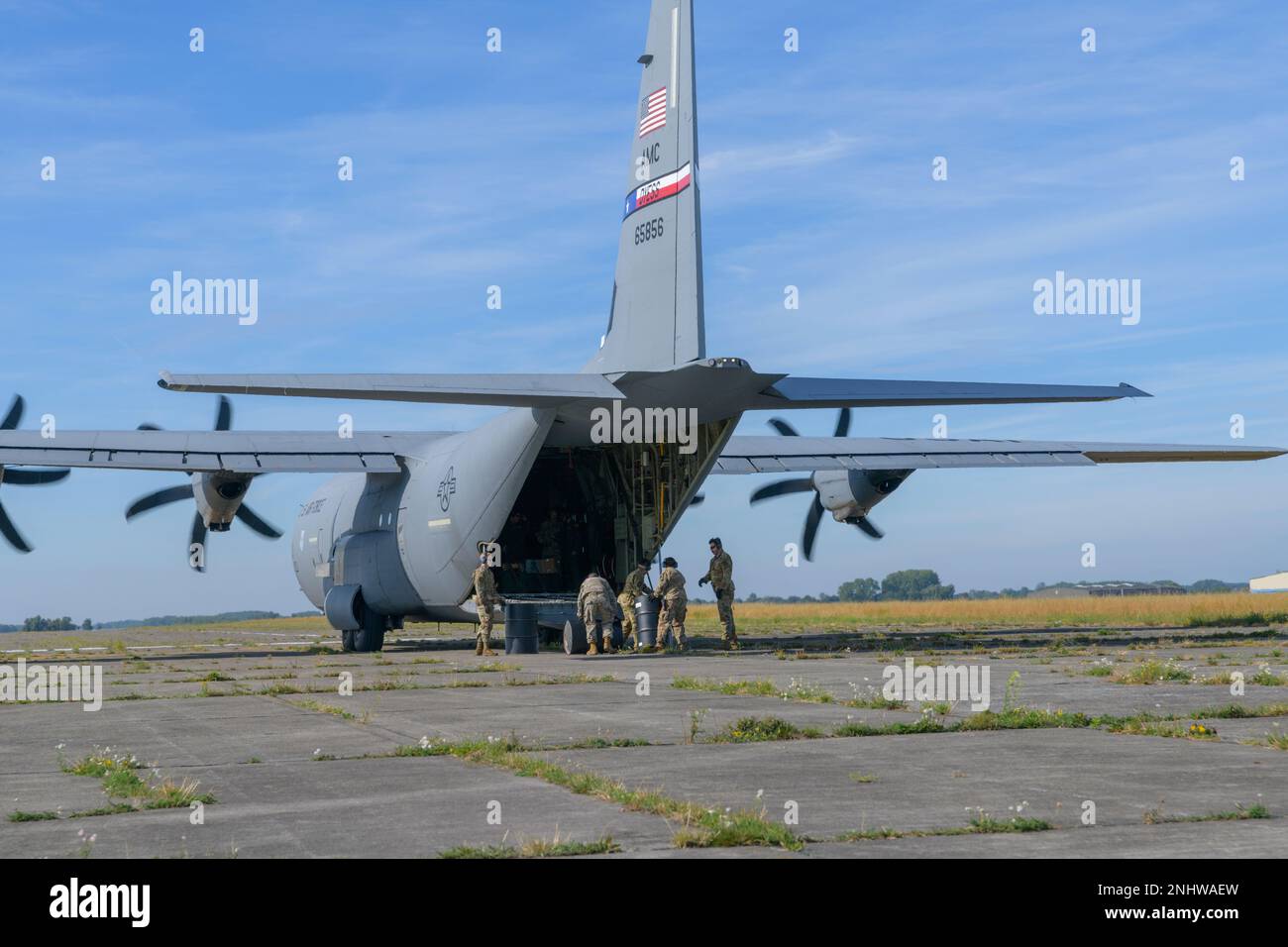 U.S. Airmen assigned to the 424th Air Base Squadron place barrels under ...