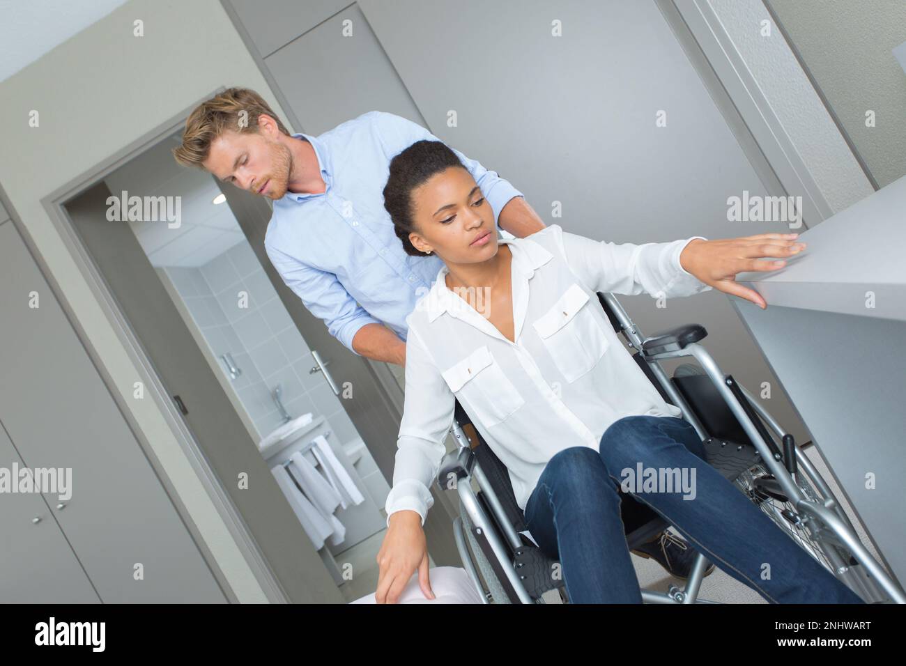 woman in wheelchair being pushed by hotel member Stock Photo - Alamy