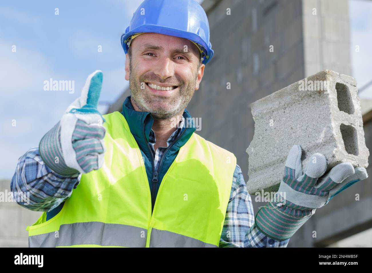 handsome construction showing a thumb-up and hodling concrete bricks ...
