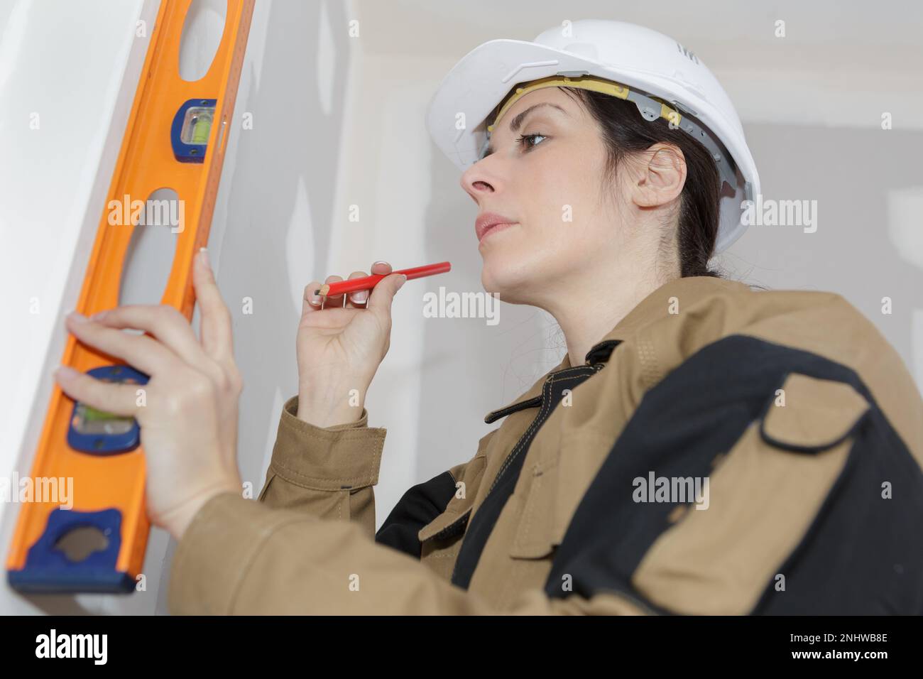 woman holding up a ruler and level marking a wall Stock Photo - Alamy