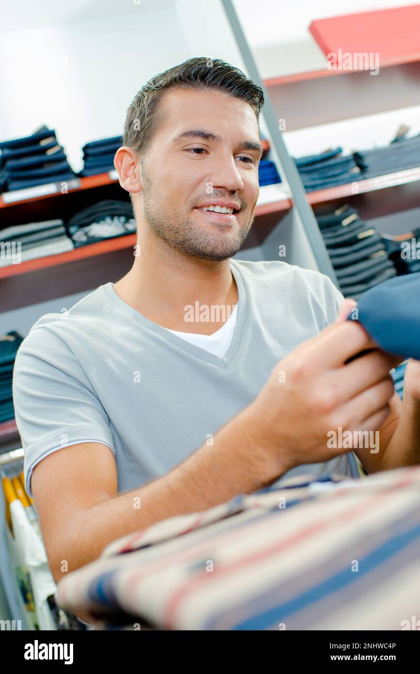 Man in clothes shop, touching fabric Stock Photo - Alamy