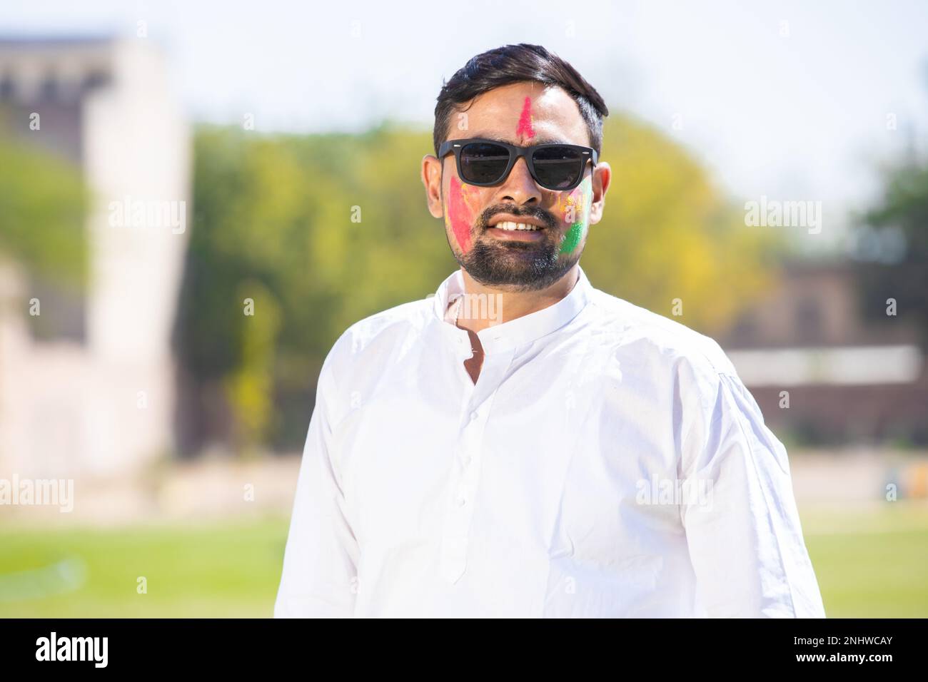 Portrait of young Indian man wearing white kurta and sunglasses ...