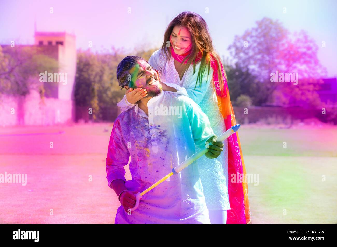 Happy young Indian couple having fun playing with colorful powder color ...