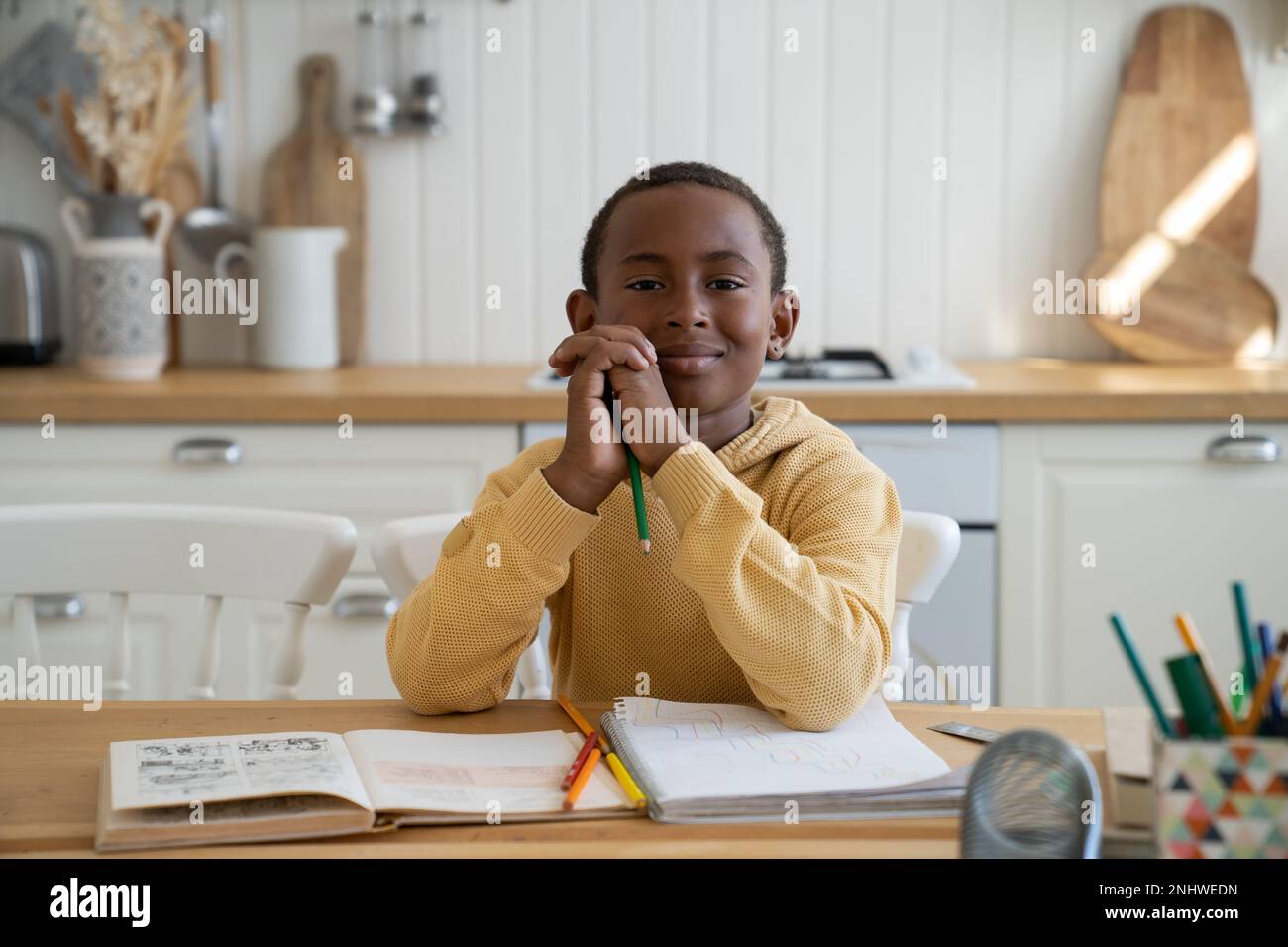 Happy portrait of smiling Black content boy study at home with textbook ...