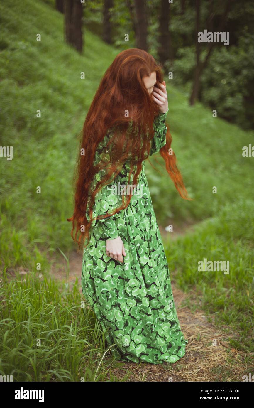 Close up ginger haired woman in long dress standing on pathway portrait ...