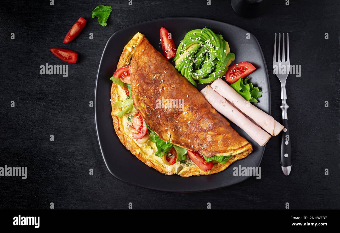 Keto breakfast. Omelette tomato, olives and avocado, ham. Ketogenic ...
