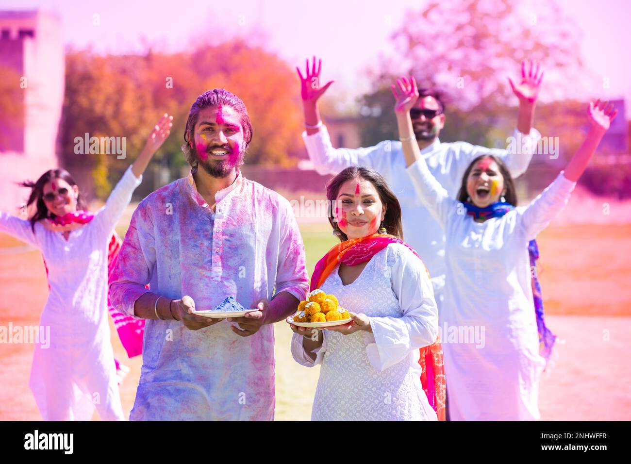 Happy young indian family wearing white kurta and holding plate full of ...