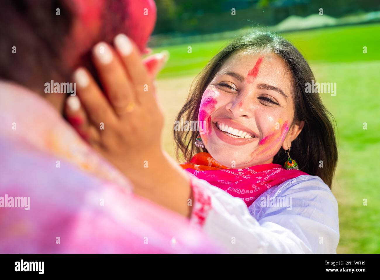 Happy young Indian couple having fun playing with colorful powder color ...