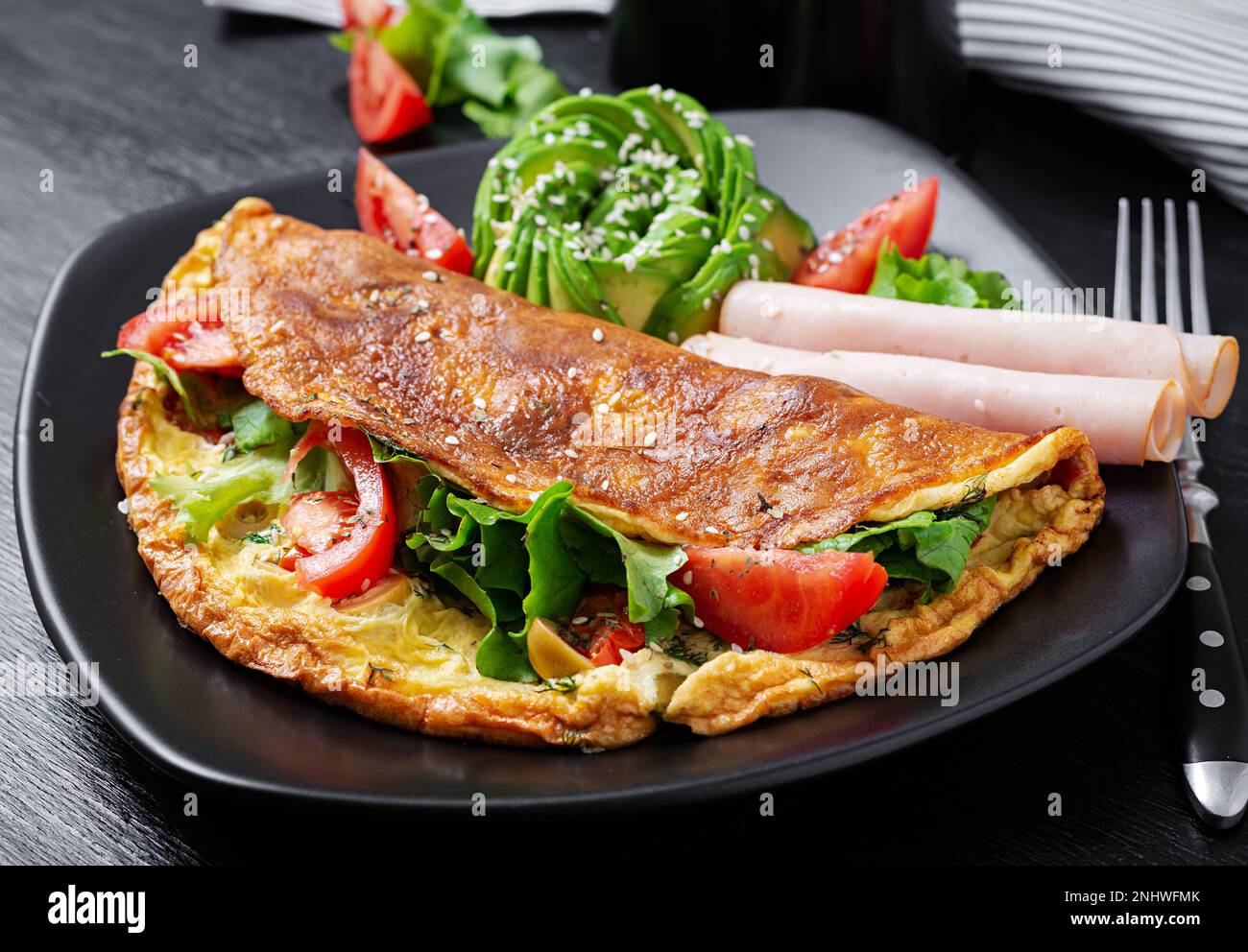 Keto breakfast. Omelette tomato, olives and avocado, ham. Ketogenic ...