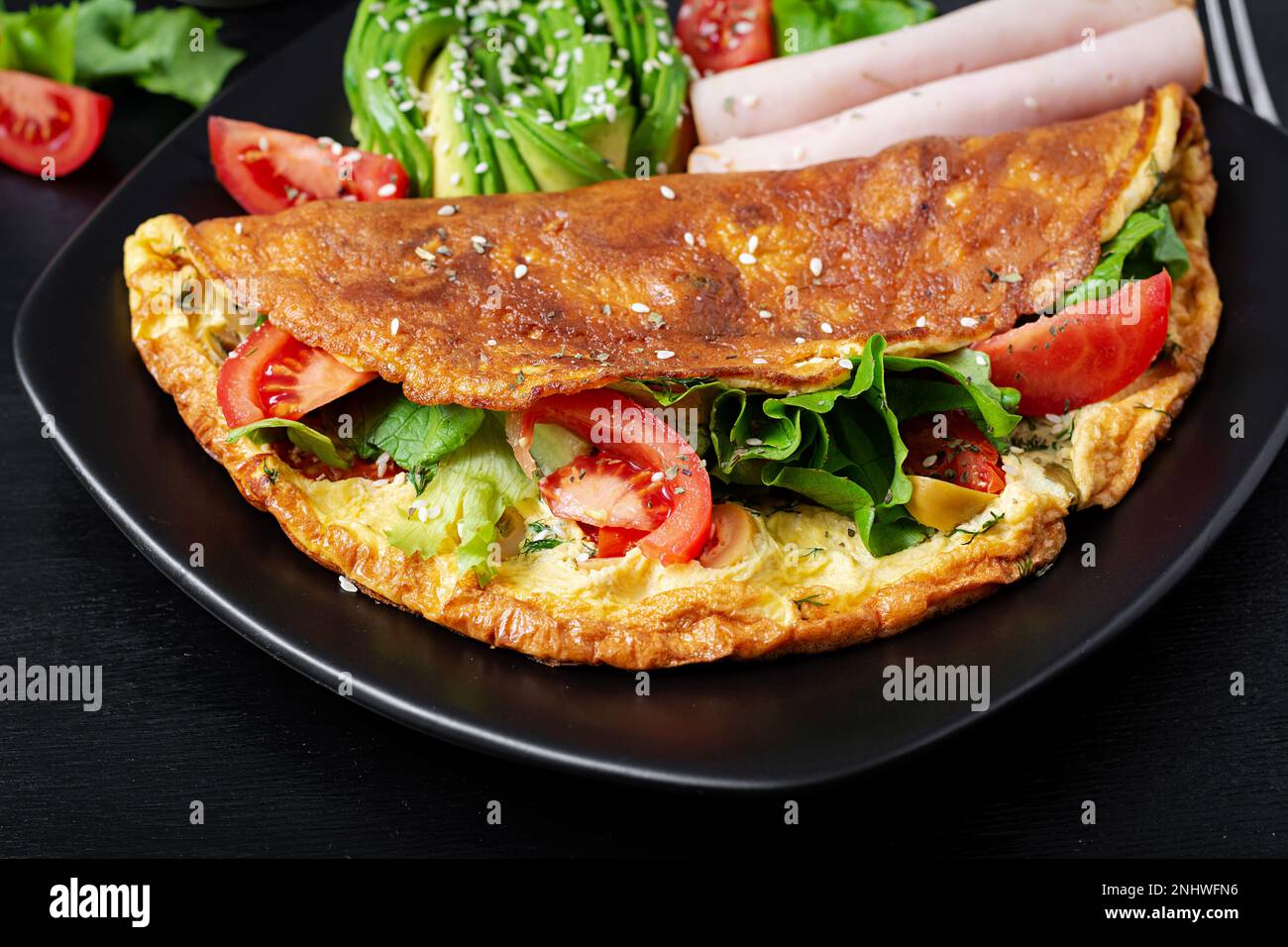 Keto breakfast. Omelette tomato, olives and avocado, ham. Ketogenic ...