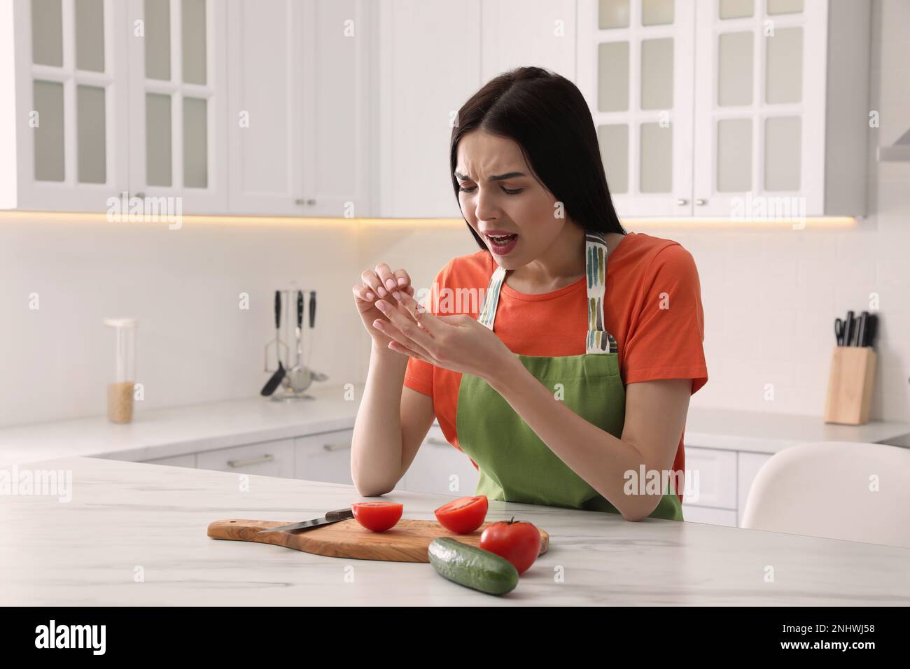 Young woman cutting finger with knife while cooking in kitchen Stock ...