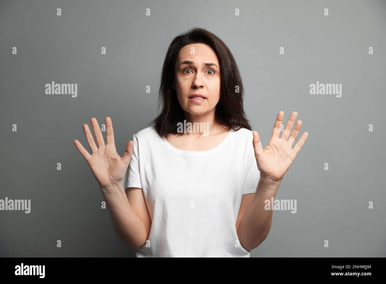 Mature woman feeling fear on grey background Stock Photo - Alamy