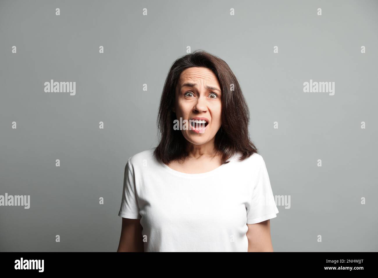 Mature woman feeling fear on grey background Stock Photo - Alamy