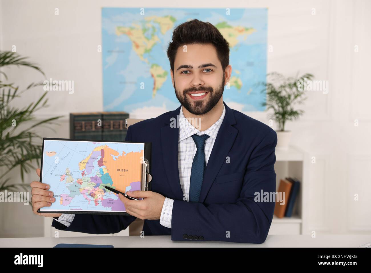 Happy manager showing map at desk in travel agency Stock Photo - Alamy