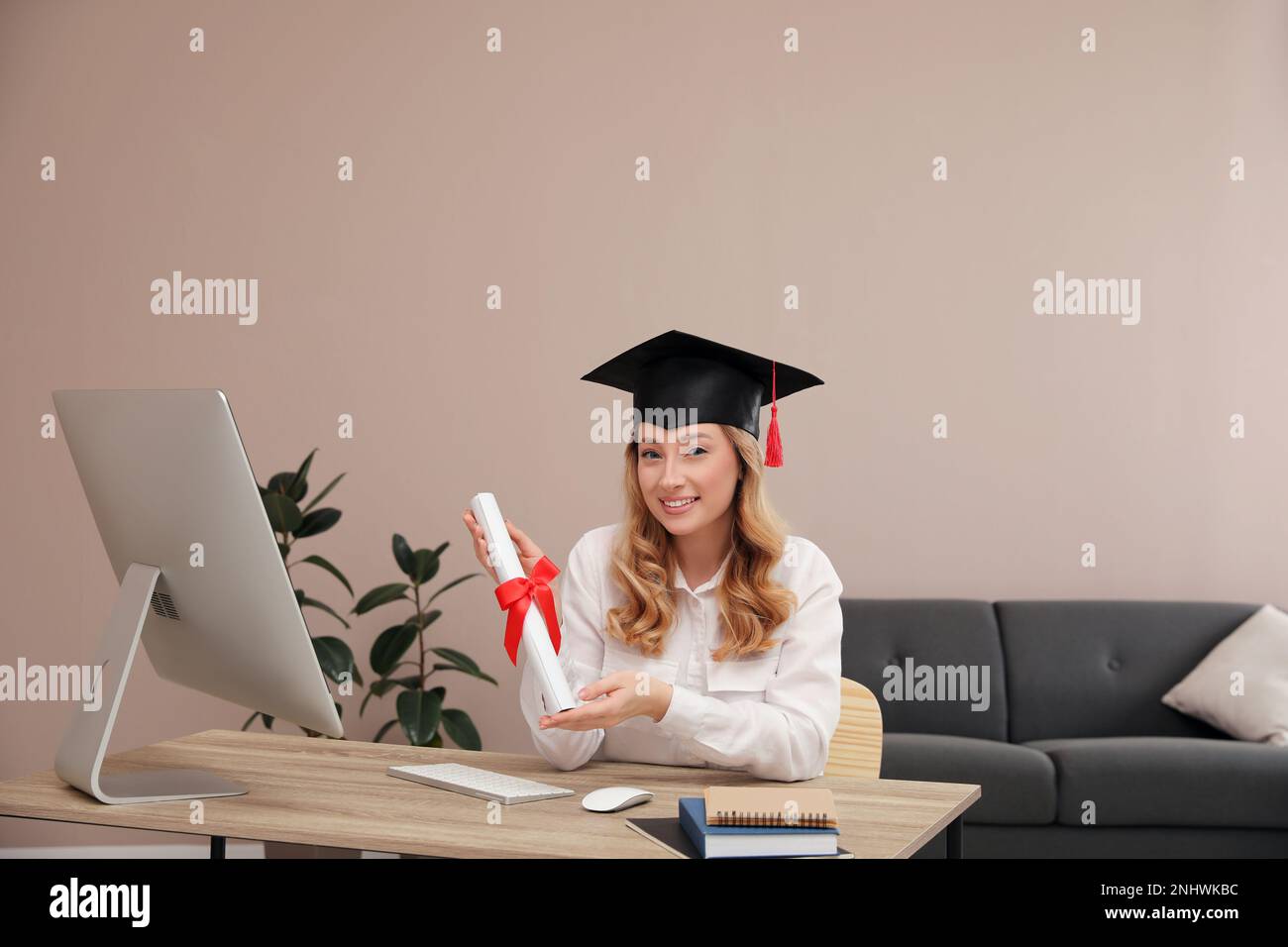 Happy student with graduation hat and diploma at workplace in office ...