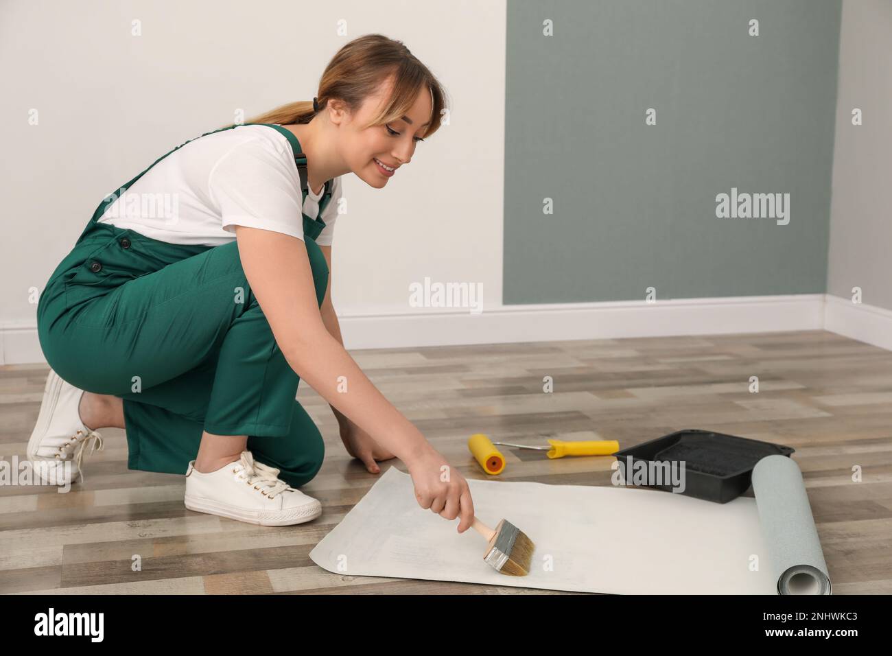 Worker applying glue onto wall paper sheet on floor indoors Stock Photo ...