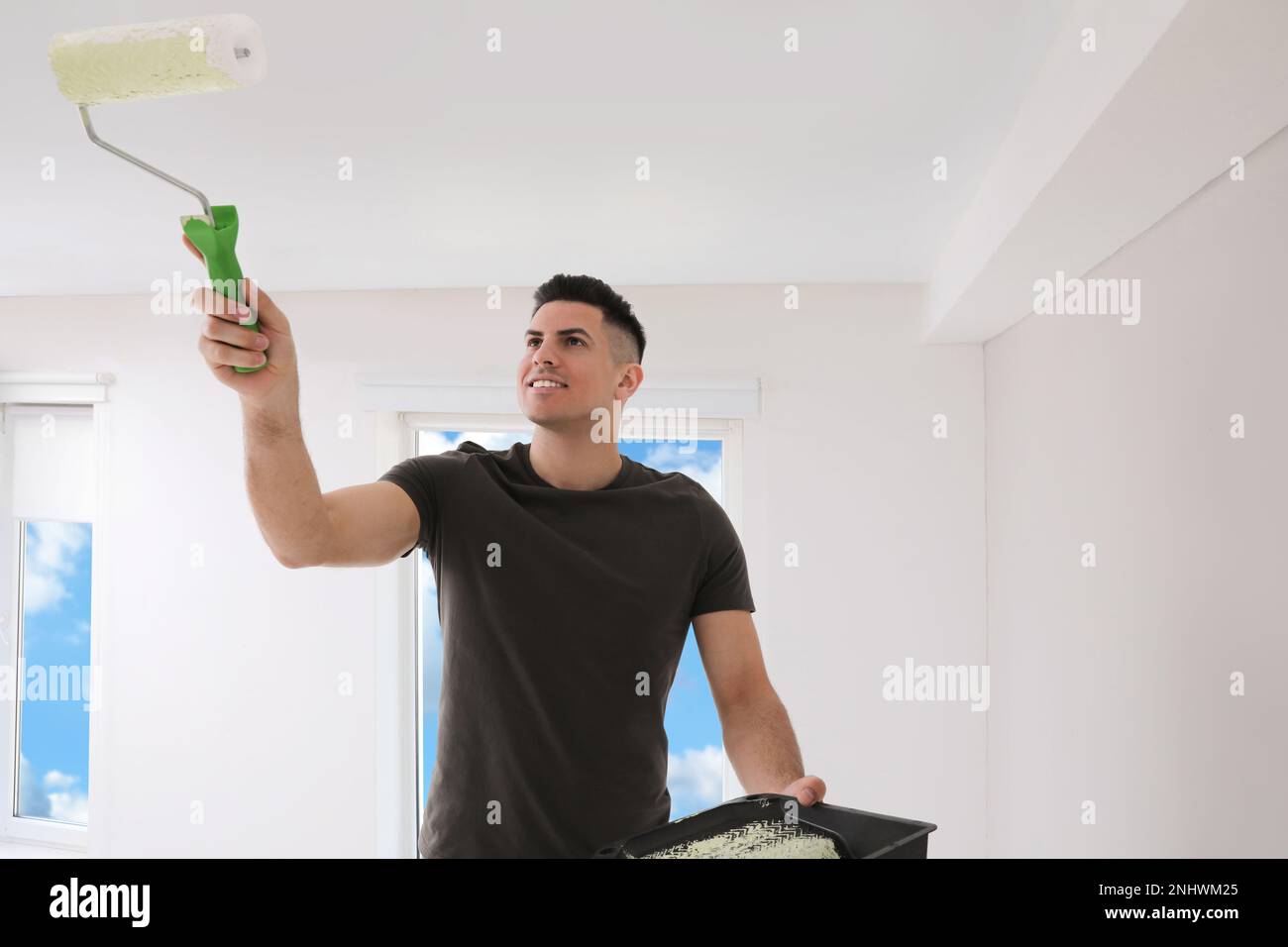 Man painting ceiling with roller in room. Space for text Stock Photo ...