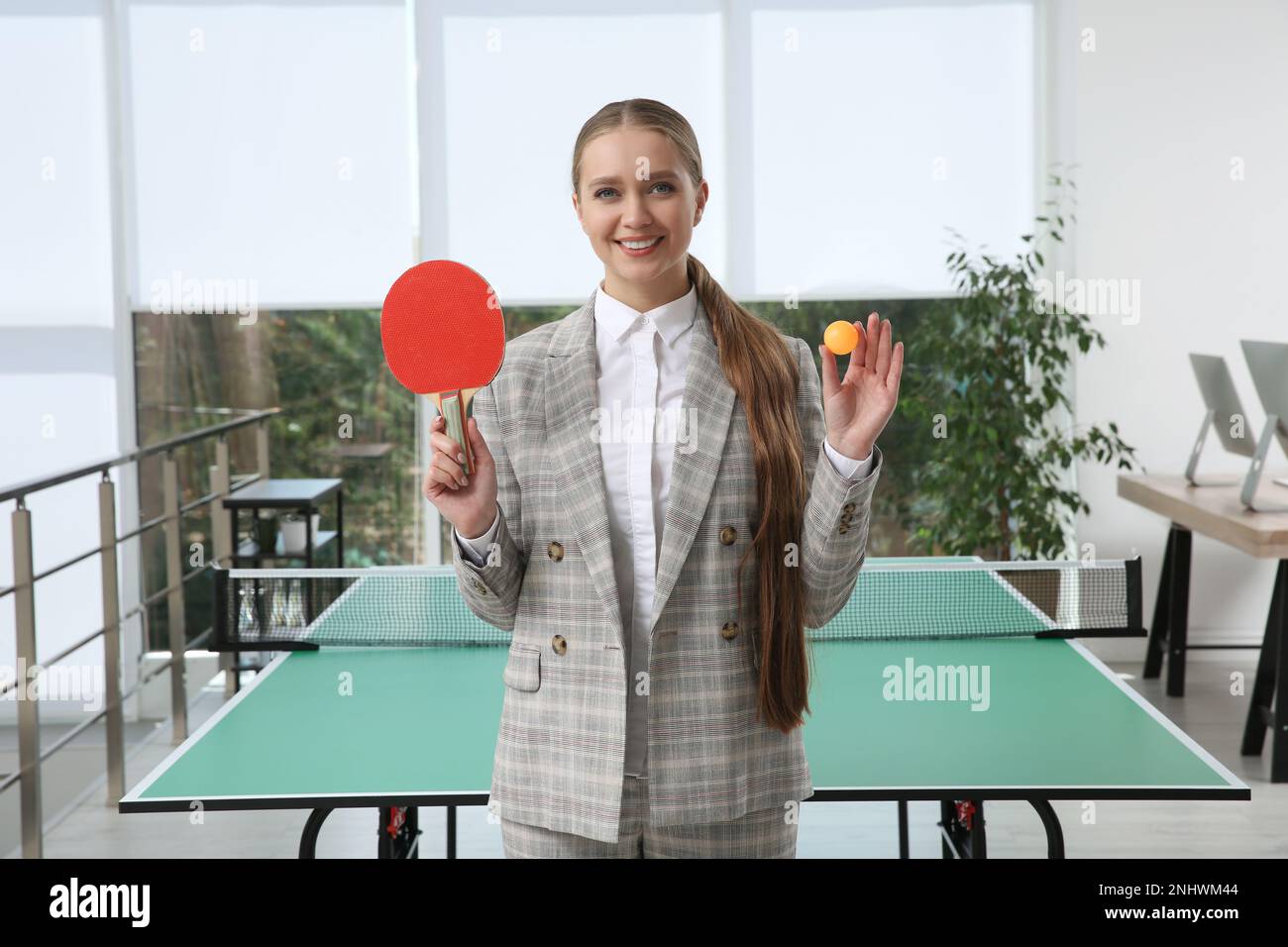 Business woman with tennis racket and ball near ping pong table in ...