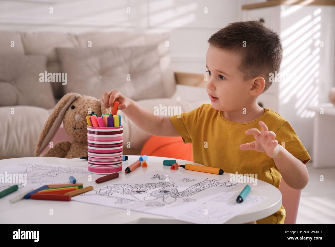 Cute child coloring drawing at table in room Stock Photo - Alamy