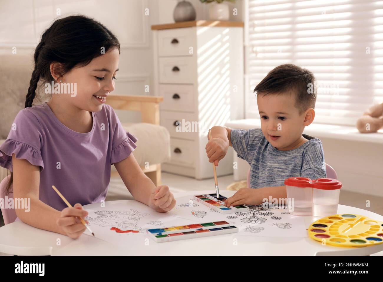 Cute children coloring drawing at table in room Stock Photo - Alamy