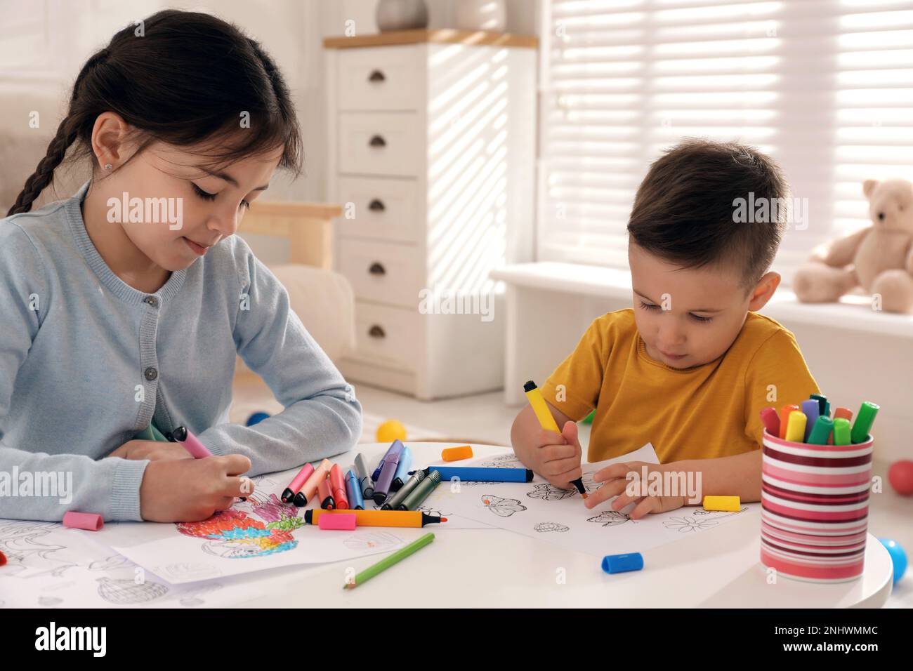 Cute children coloring drawing at table in room Stock Photo - Alamy