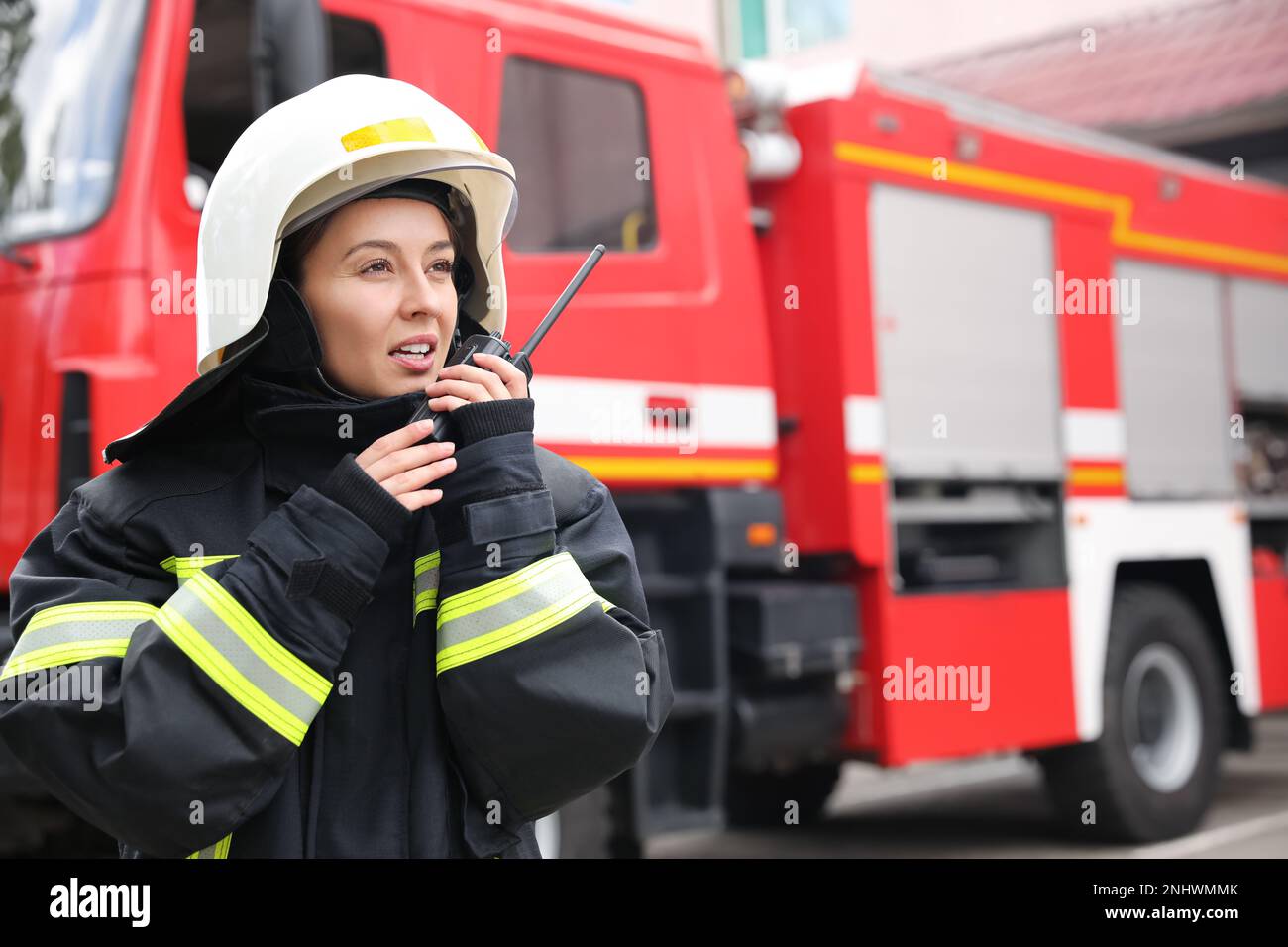 Firefighter in uniform using portable radio set near fire truck ...
