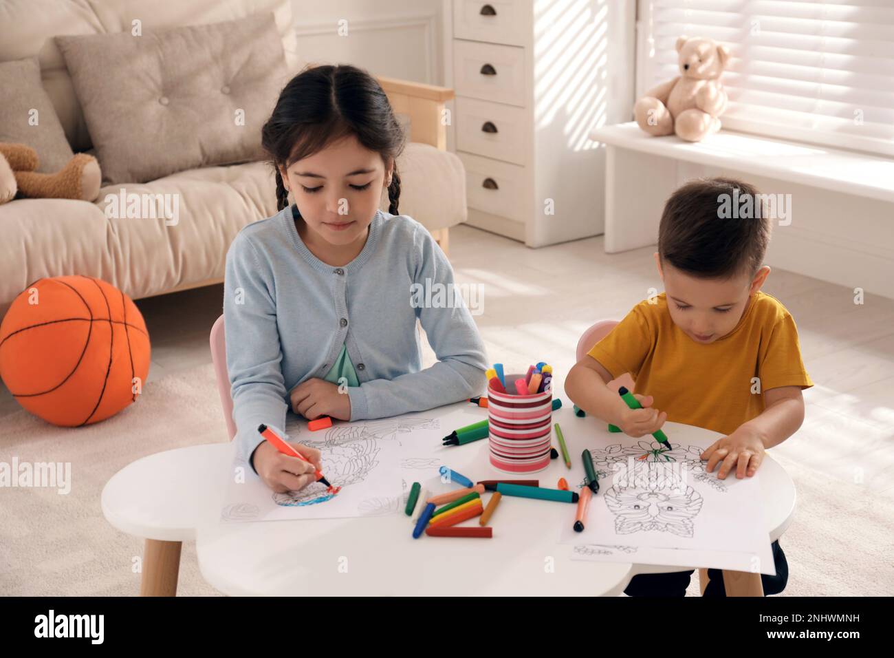 Cute children coloring drawings at table in room Stock Photo - Alamy