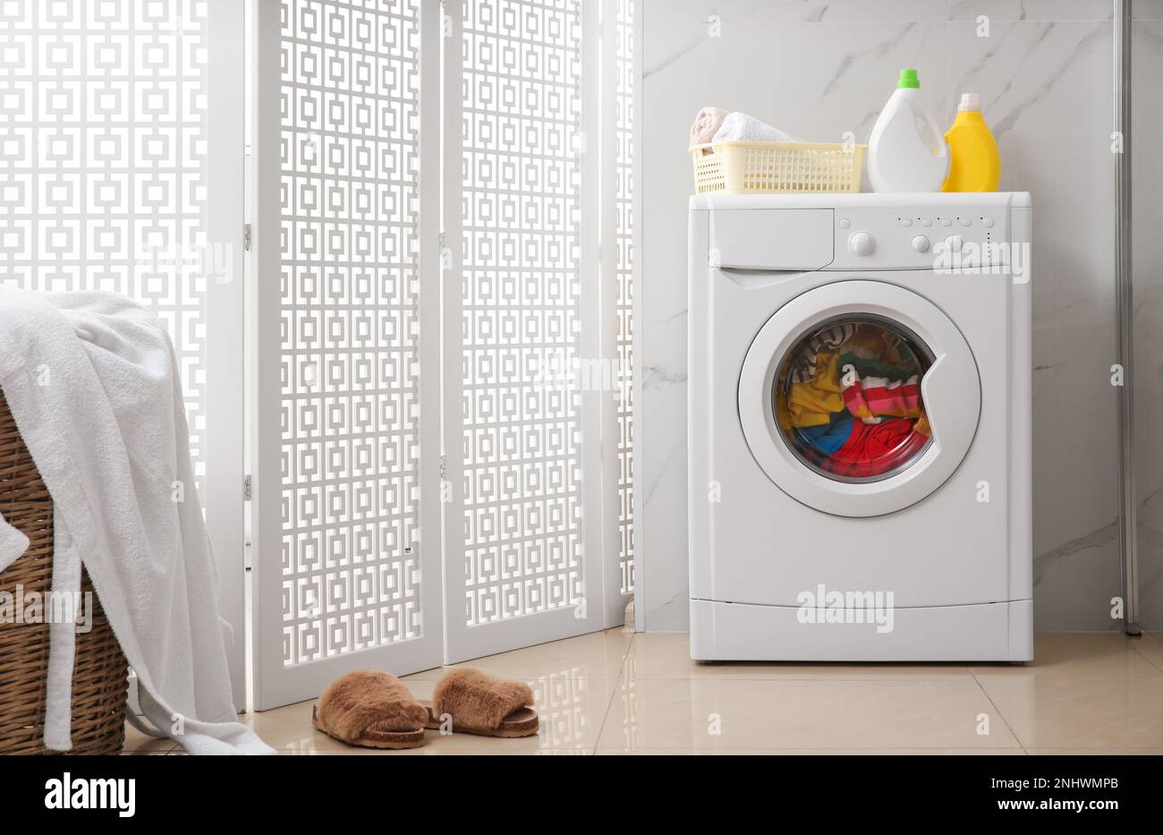 Modern washing machine with clothes in bathroom Stock Photo - Alamy