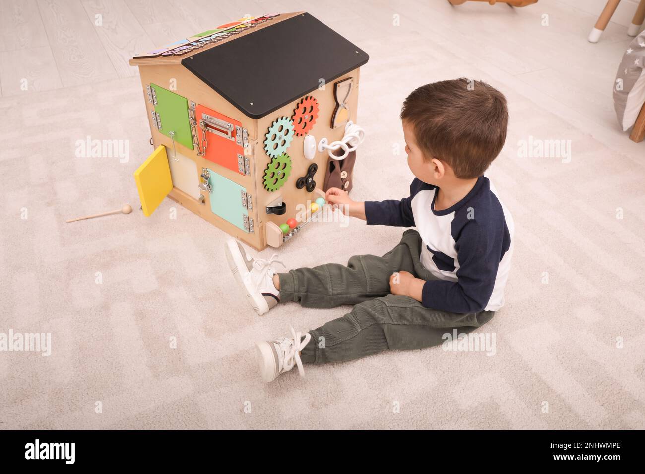 Little boy playing with busy board house on floor in room Stock Photo ...