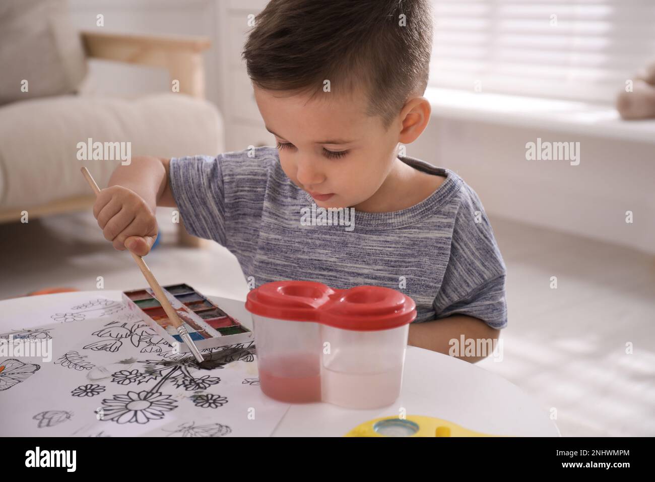 Cute child coloring drawing at table in room Stock Photo - Alamy