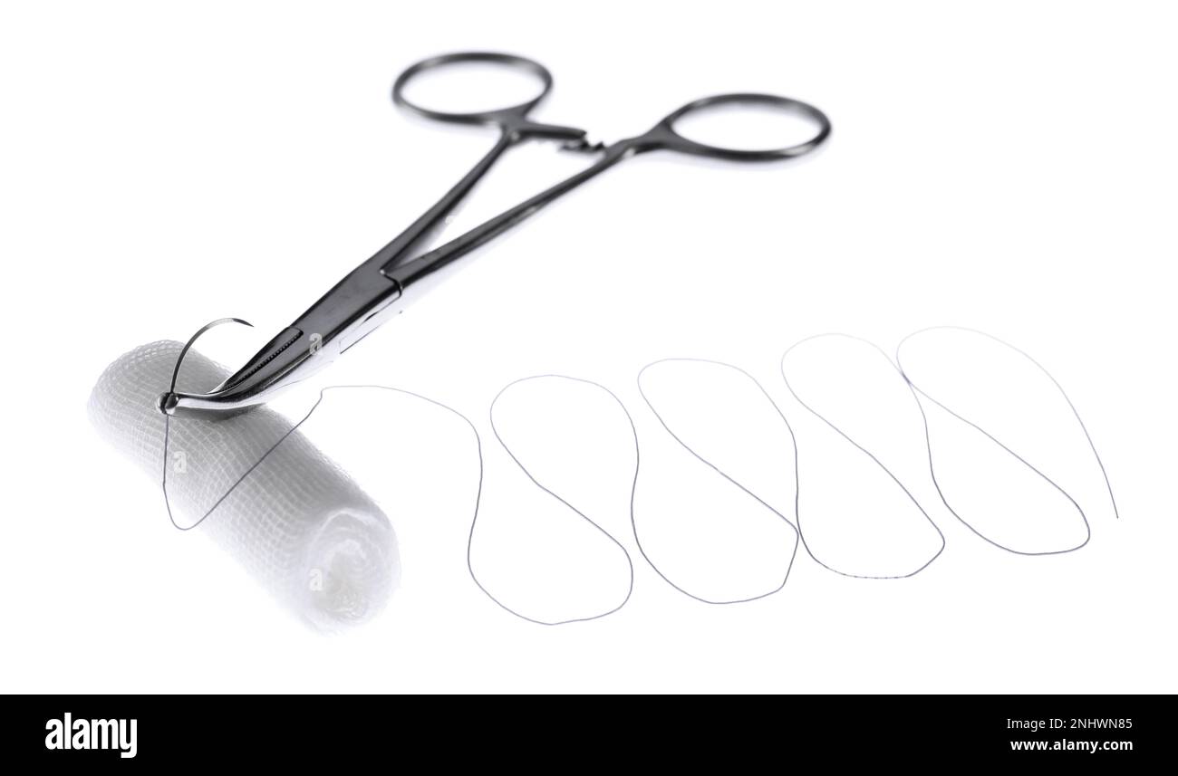 Forceps with suture thread and bandage roll on white background ...