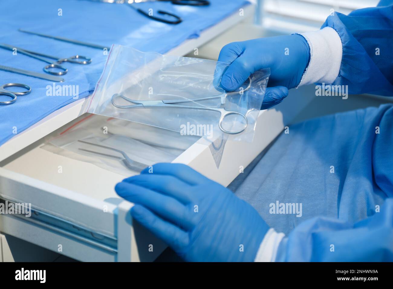 Doctor putting medical clamps into drawer indoors, closeup. Table with ...
