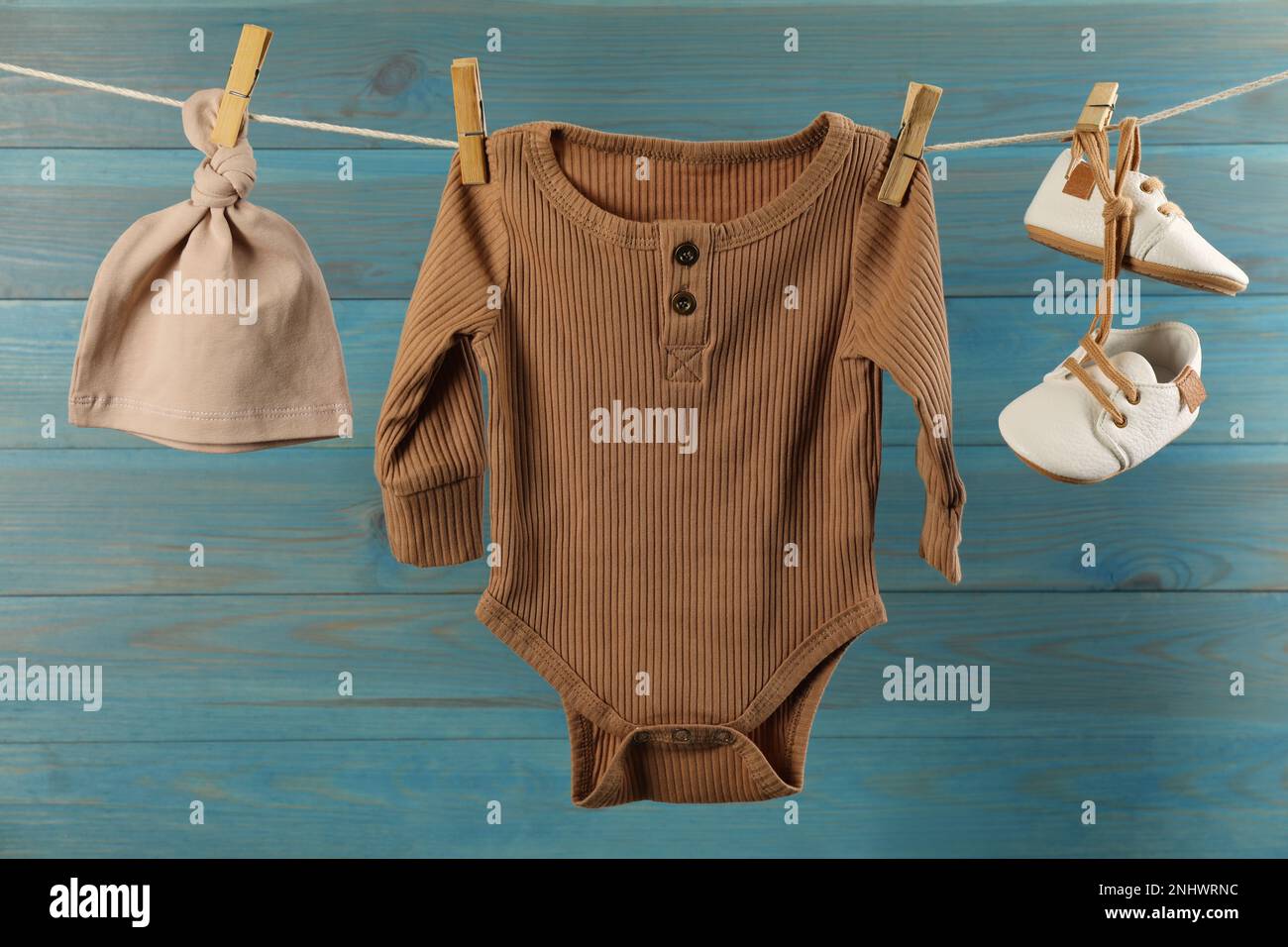 Baby clothes hanging on washing line near light blue wooden wall Stock ...