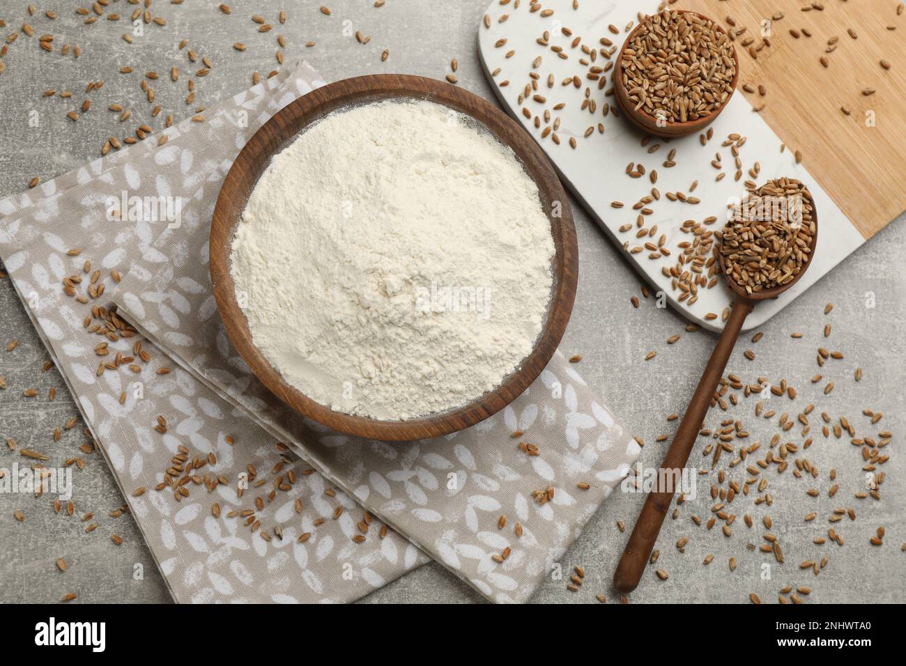 Flat lay composition with flour and wheat kernels on light grey table ...