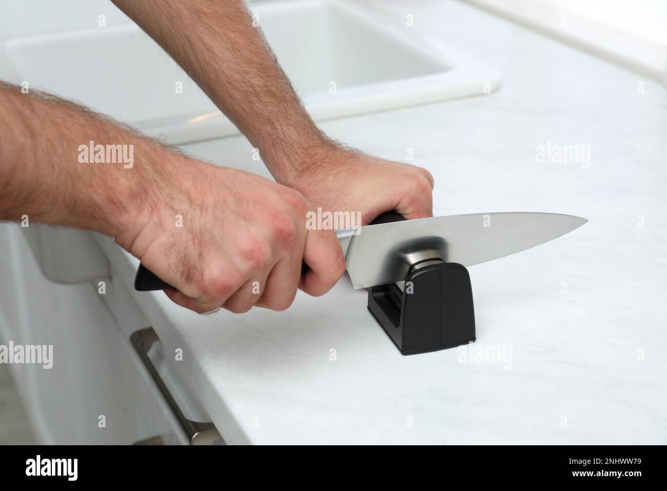 Man sharpening knife at white table indoors, closeup Stock Photo - Alamy