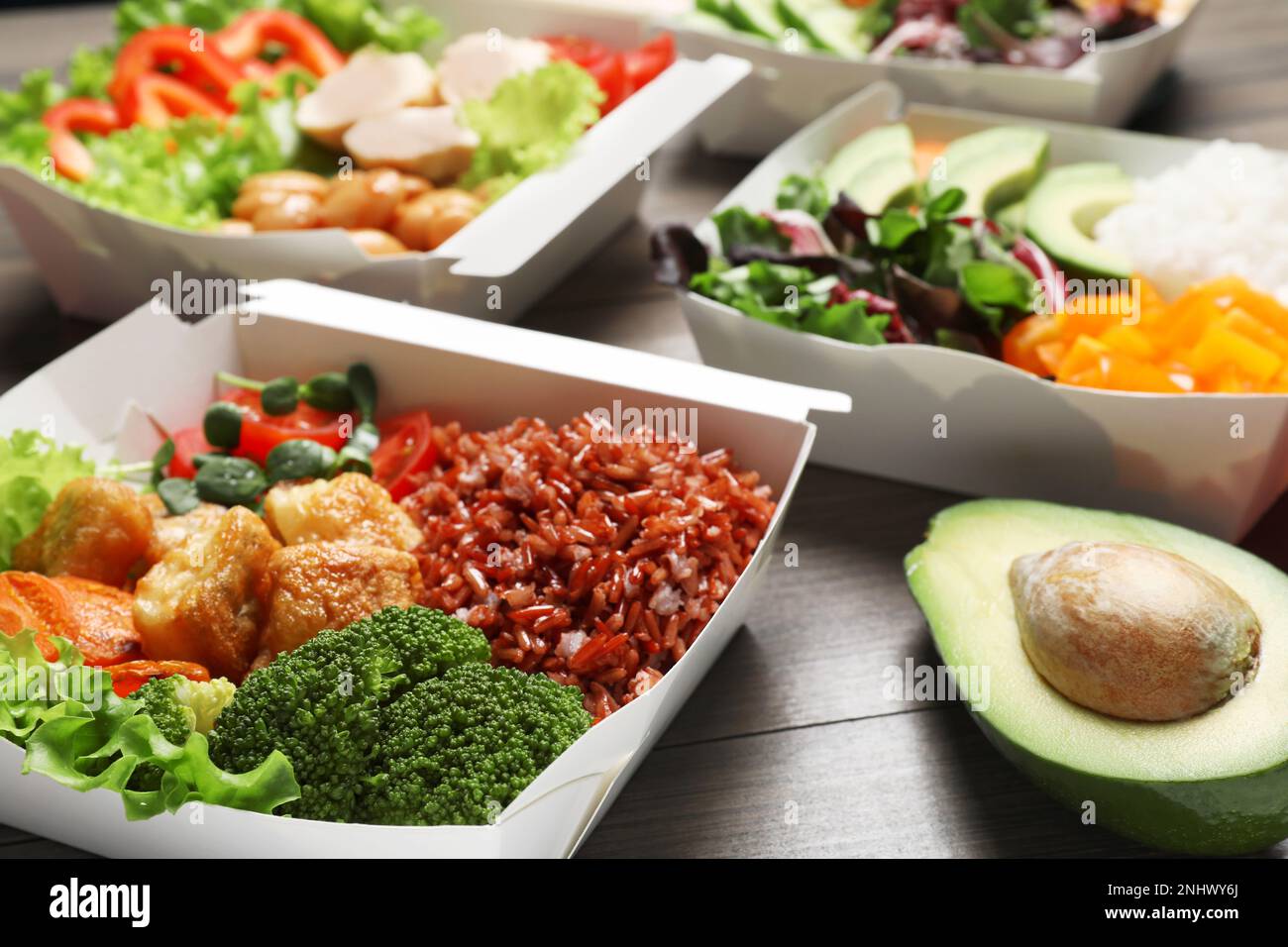 Different healthy meals in takeaway boxes on wooden table, closeup ...