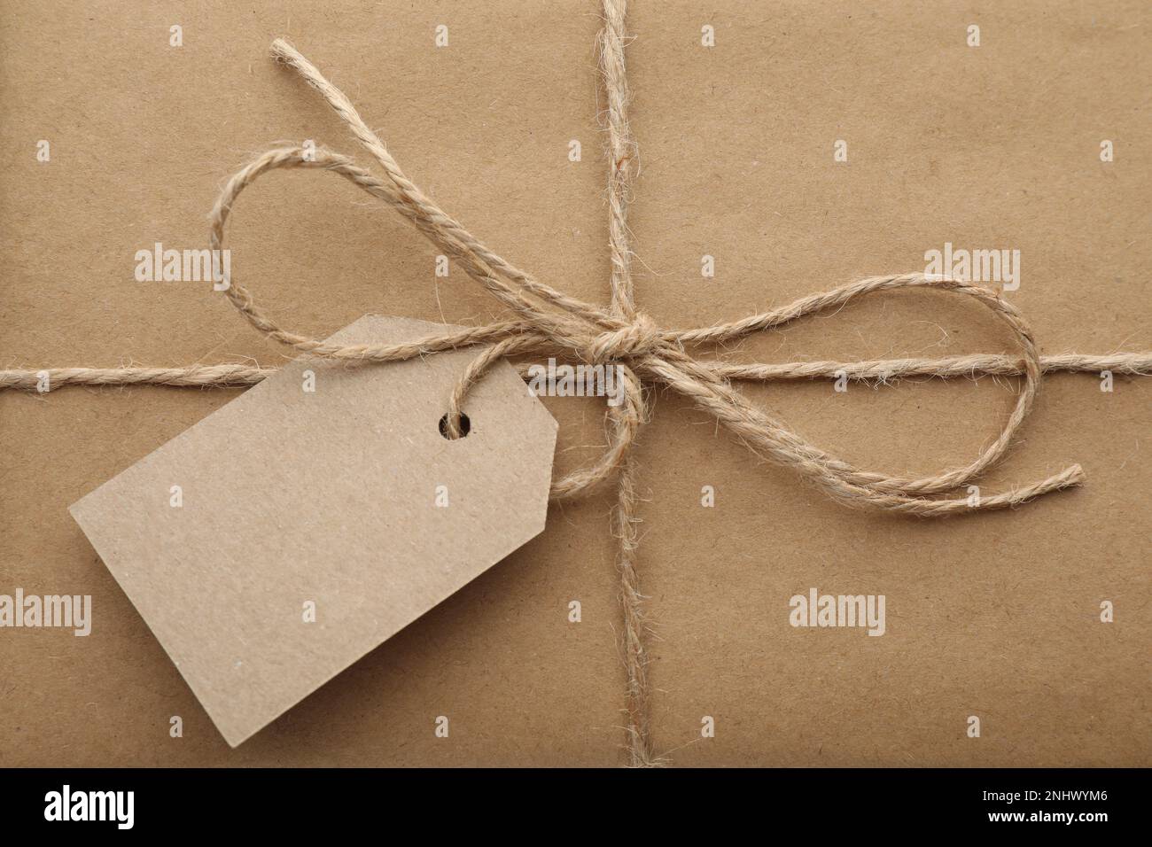 Parcel wrapped in kraft paper with tag as background, closeup Stock ...