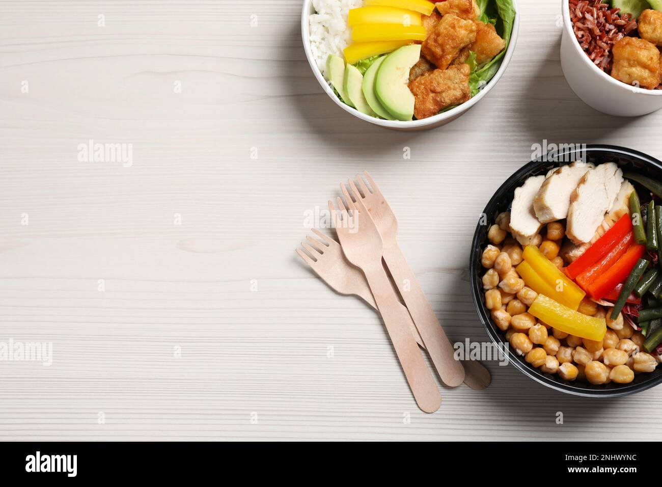 Different healthy meals in takeaway containers and wooden forks on ...