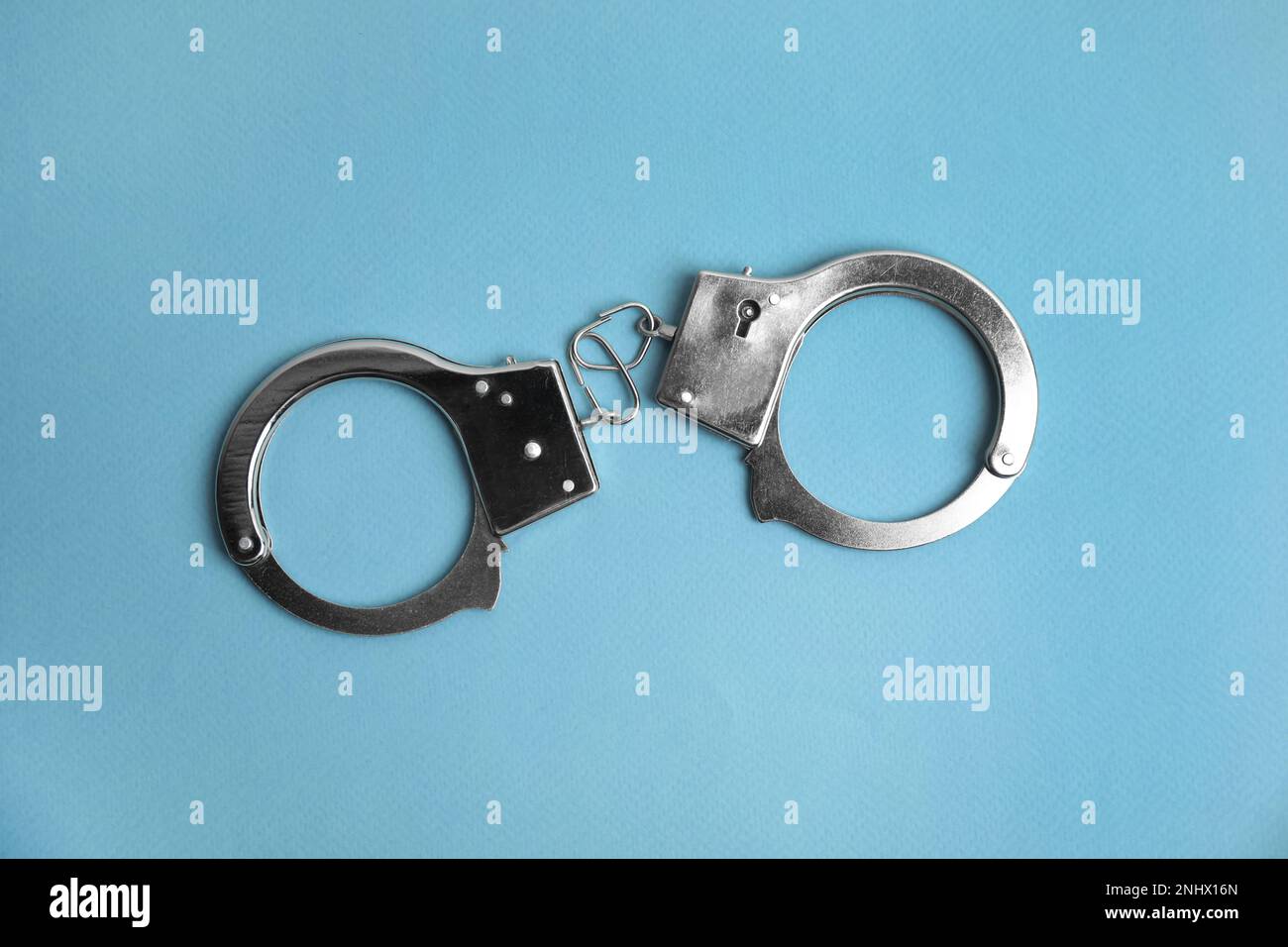 Classic chain handcuffs on light blue background, top view Stock Photo ...