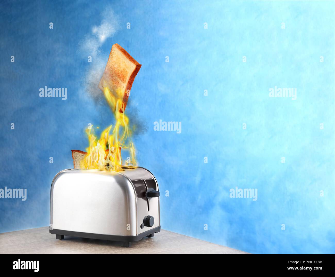 Toaster flaming up while cooking slices of bread on white wooden table ...