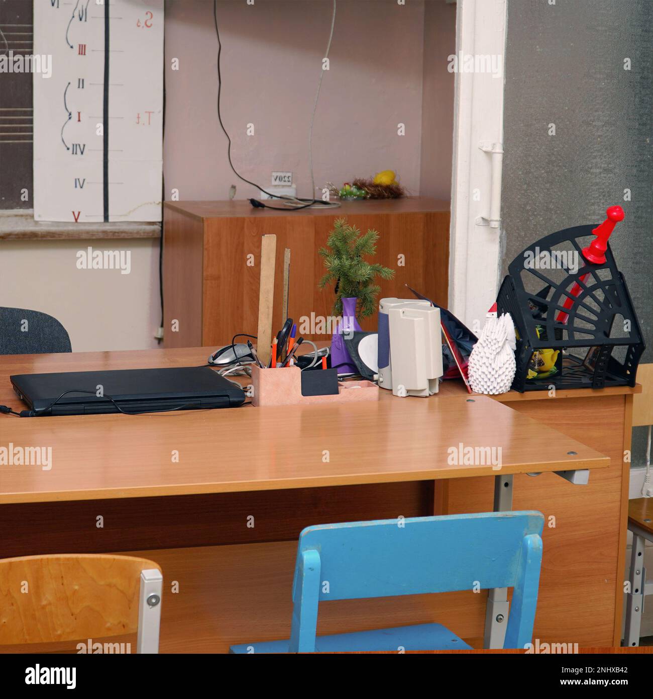 Teacher's desk with a laptop and a stack of papers in the classroom in ...